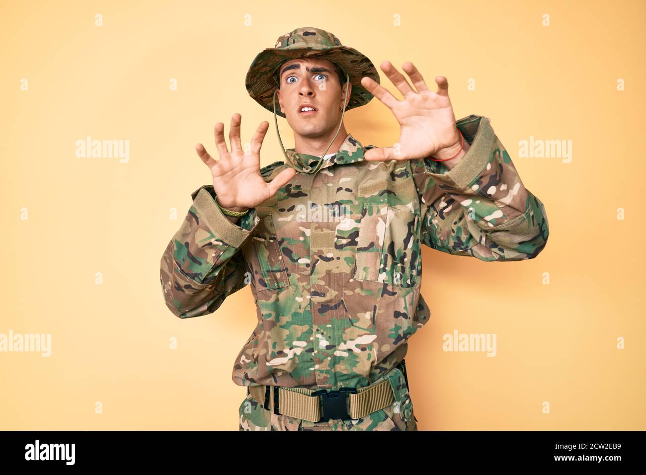 Young handsome man wearing camouflage army uniform afraid and terrified ...