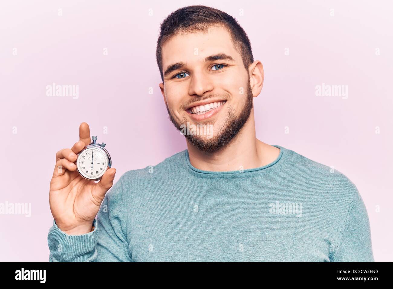 Young handsome man holding stopwatch looking positive and happy ...