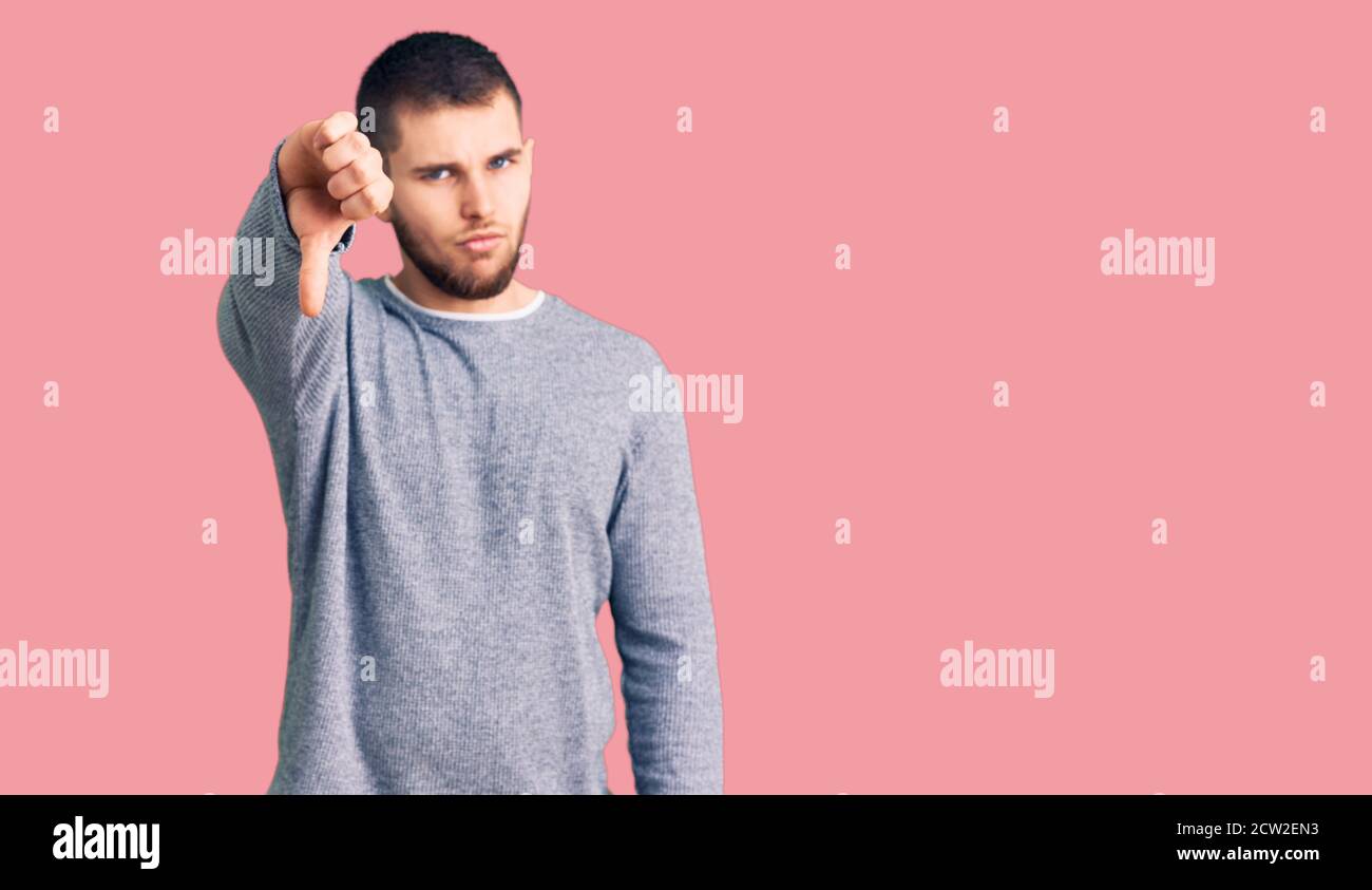 Young handsome man wearing casual sweater looking unhappy and angry ...