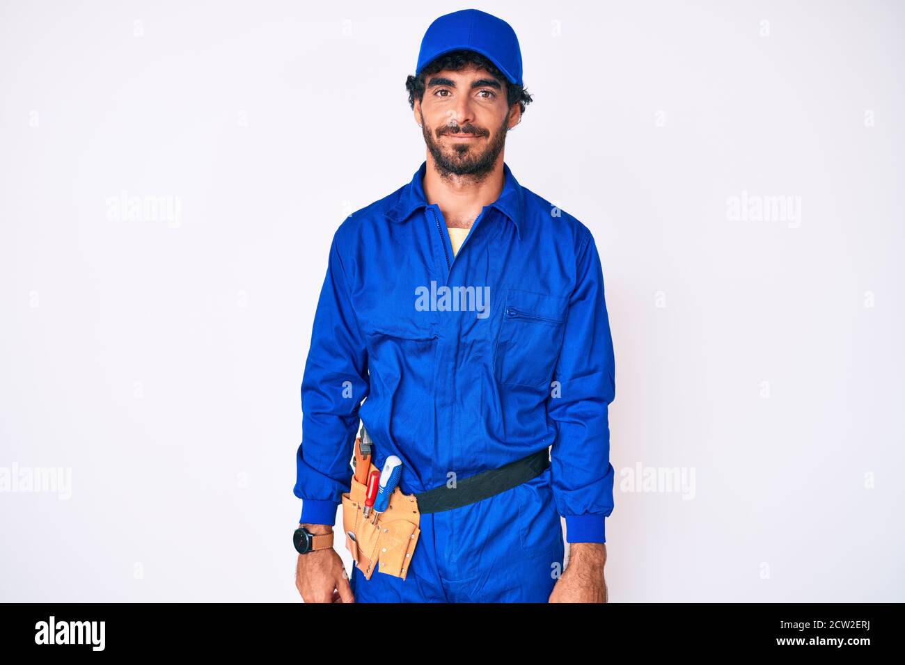 Handsome young man with curly hair and bear weaing handyman uniform ...