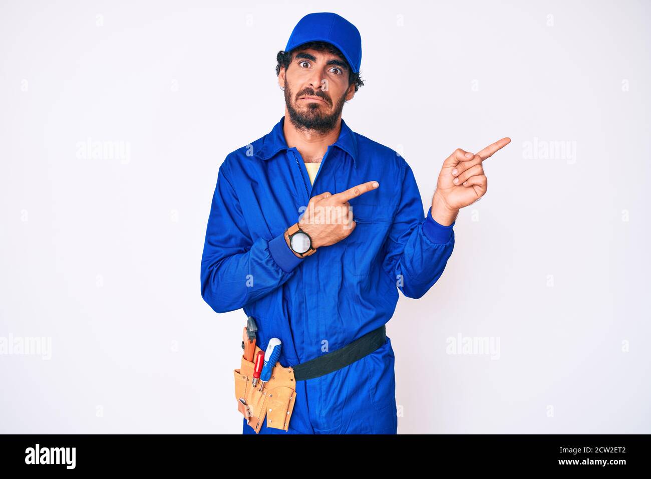 Handsome young man with curly hair and bear weaing handyman uniform ...
