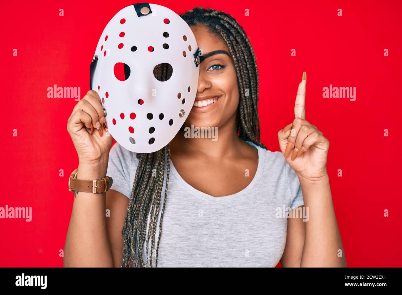 Young african american woman with braids wearing hockey mask surprised ...