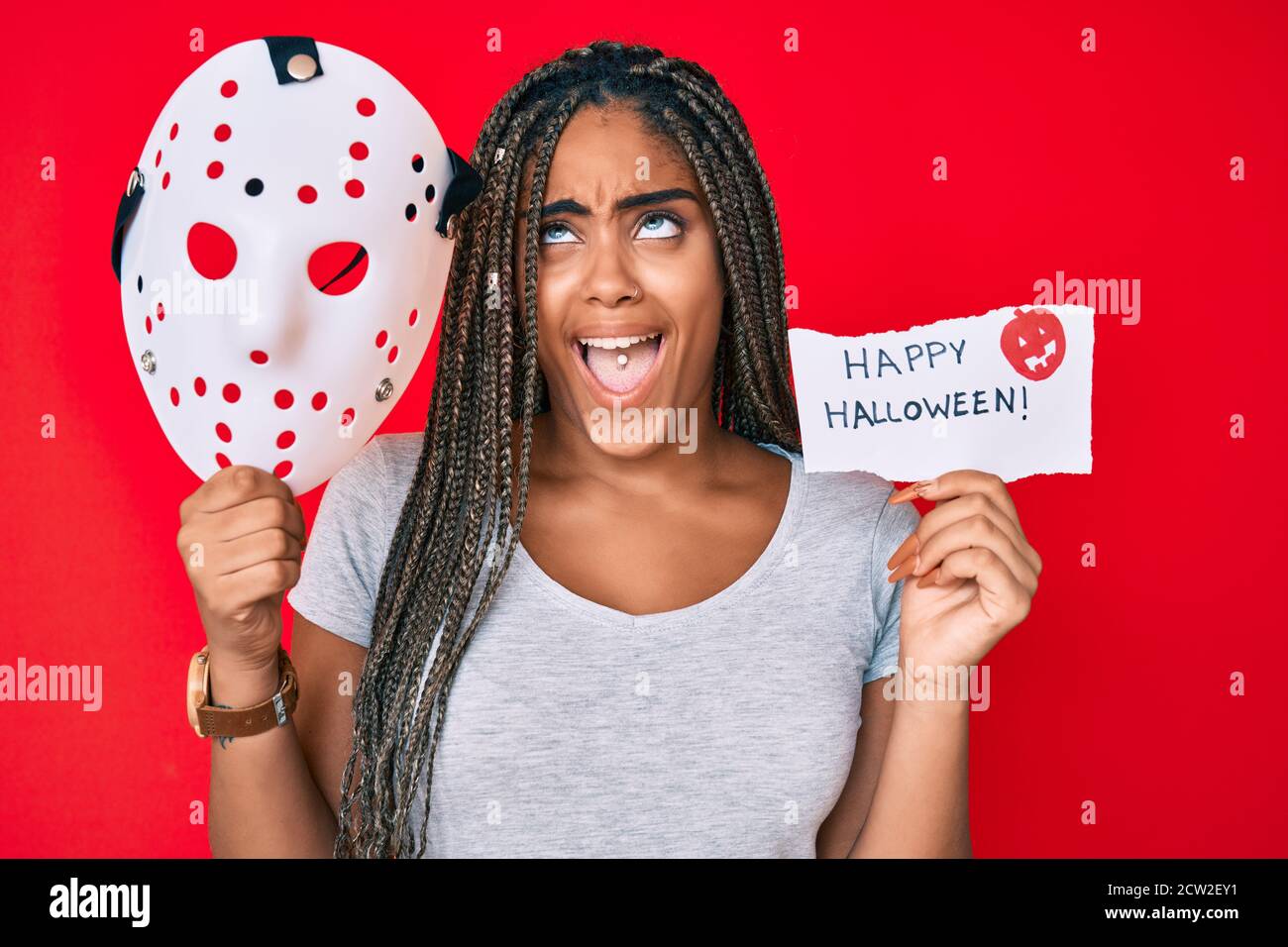 Young african american woman with braids holding halloween banner and ...