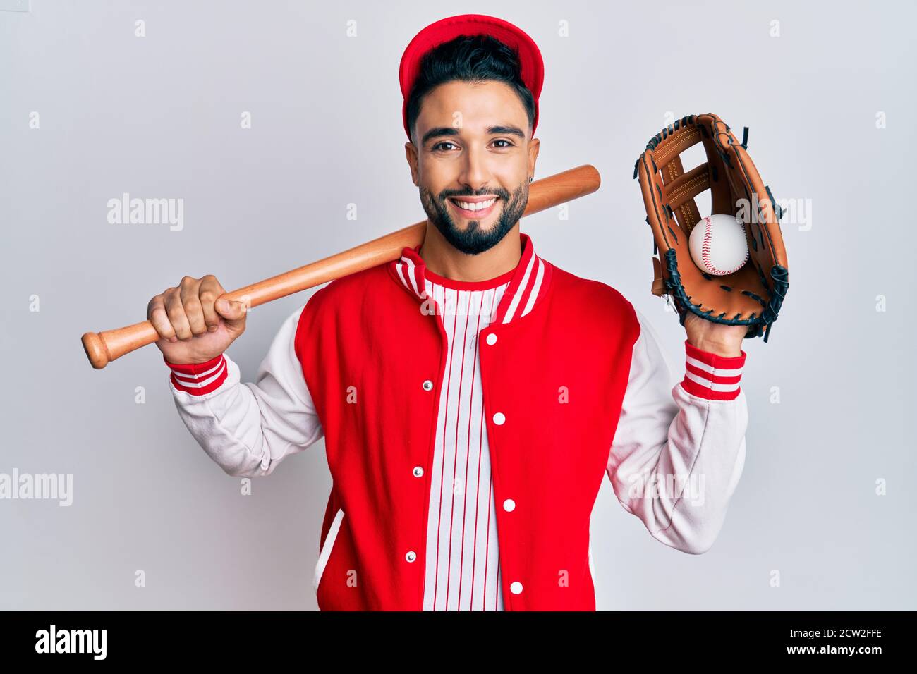 Young man with beard playing baseball holding bat and ball smiling with ...