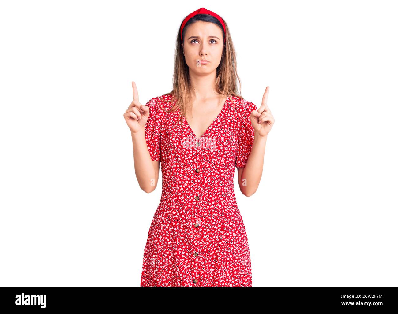 Young beautiful girl wearing dress and diadem pointing up looking sad ...