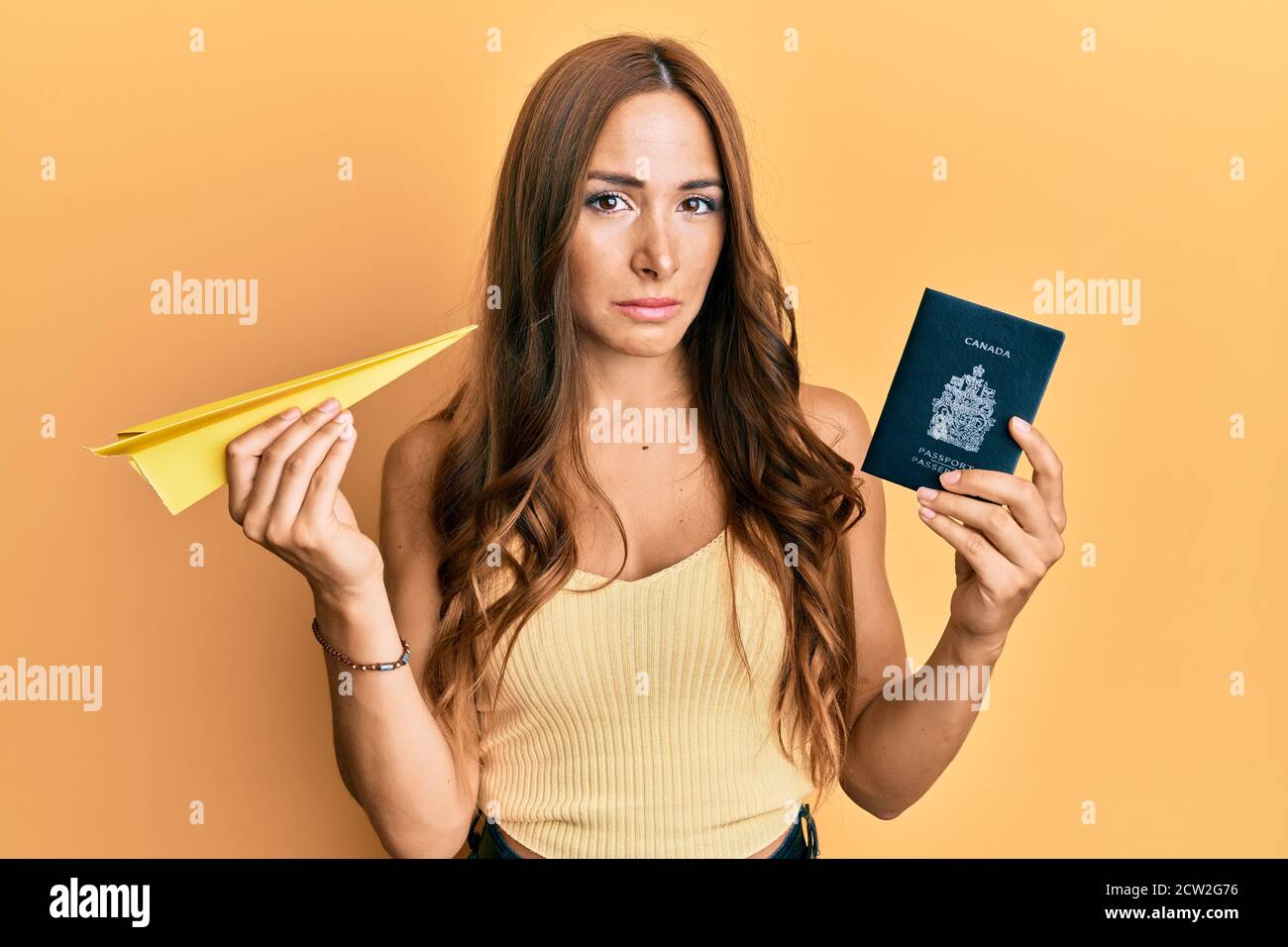 Young brunette woman holding paper airplane and canadian passport ...