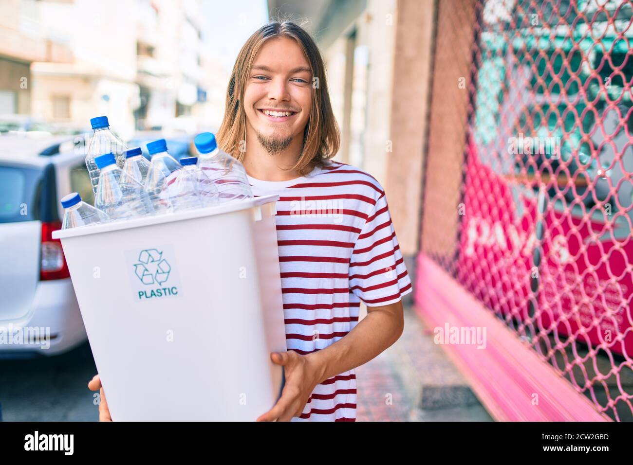 Young caucasian man with blond long hair and beard recycling plastic ...
