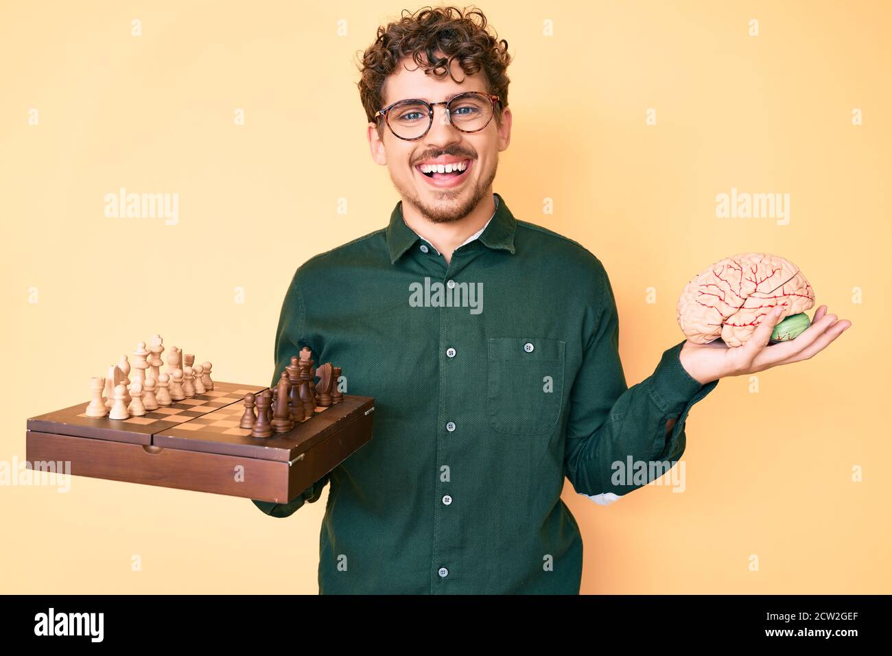 Young caucasian man with curly hair holding brain while playing chess ...