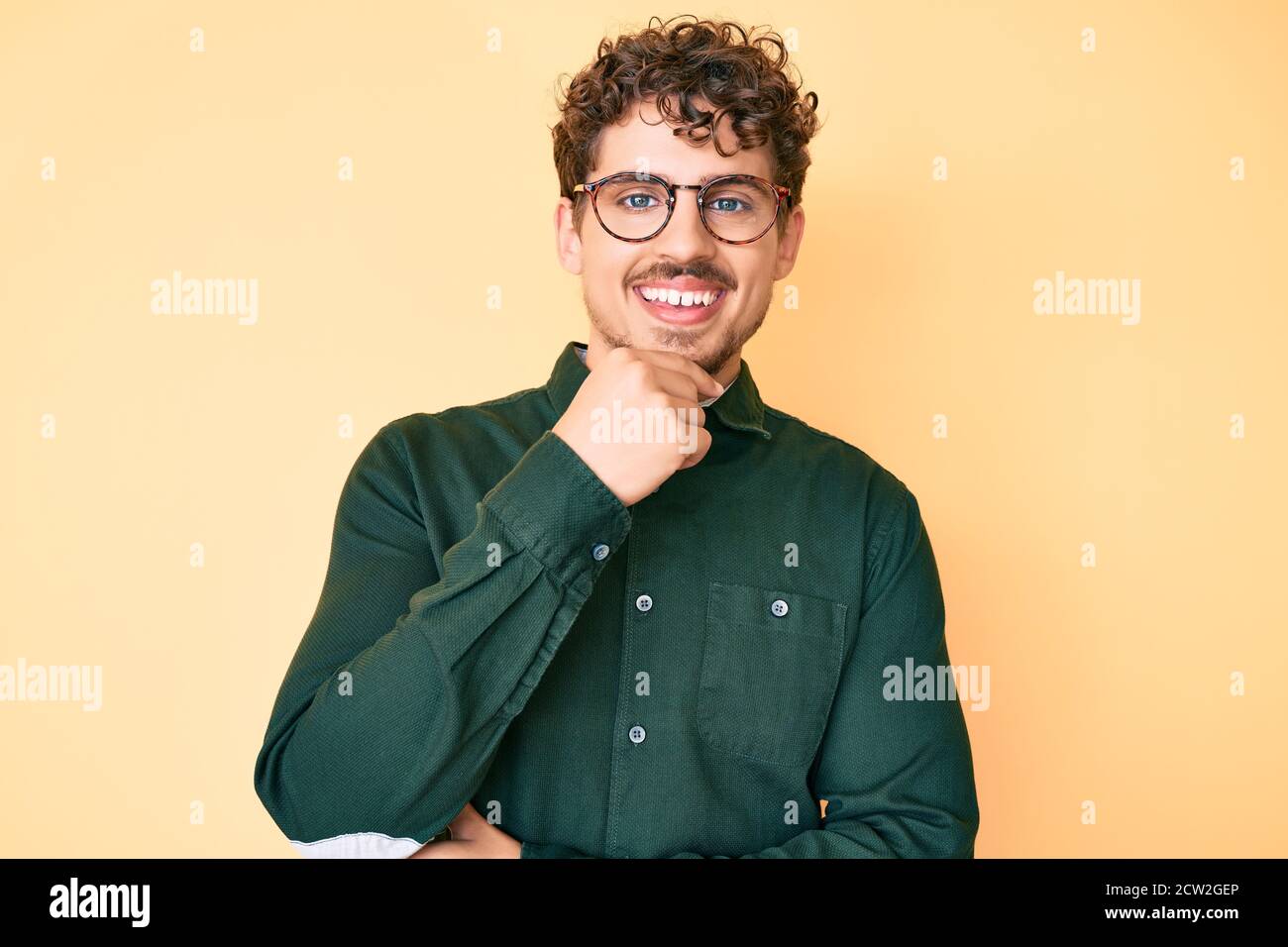 Young caucasian man with curly hair wearing casual clothes and glasses ...