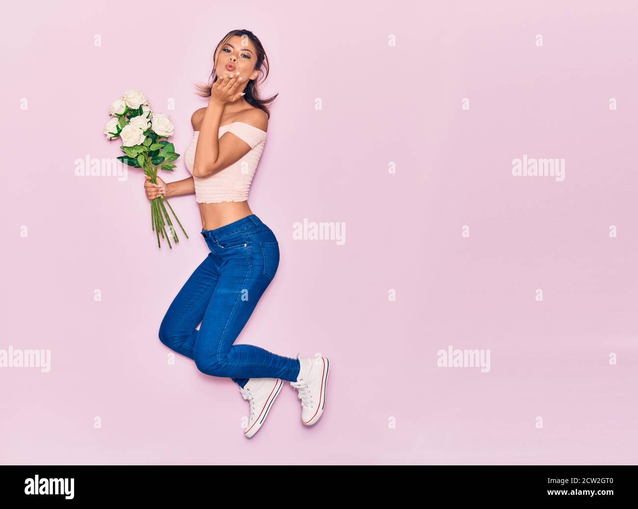 Young beautiful girl holding bouquet of flowers. Throwing kiss with ...