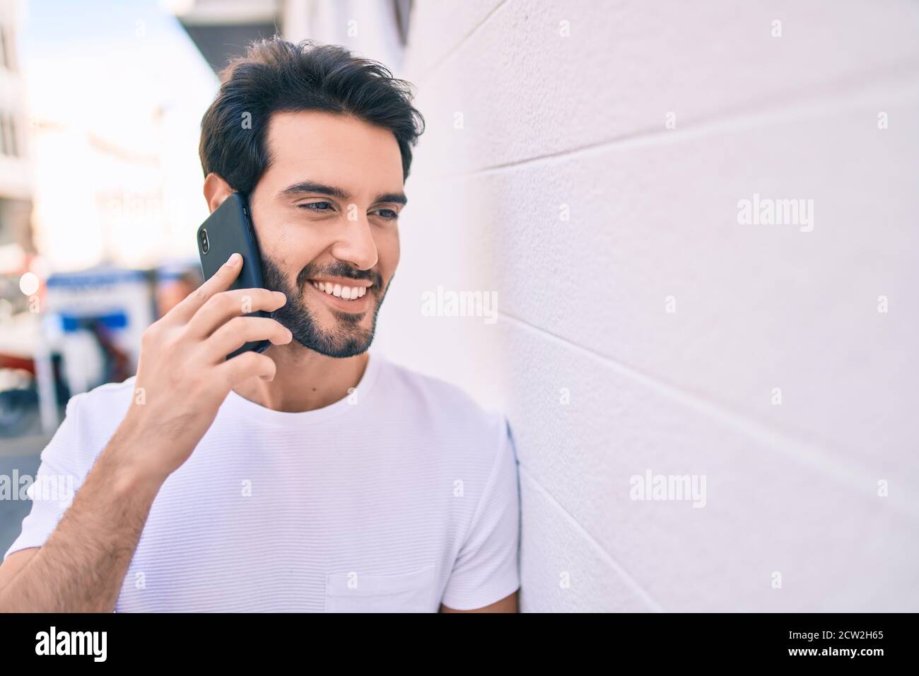 Young hispanic man smiling happy talking on the smartphone leaning on ...