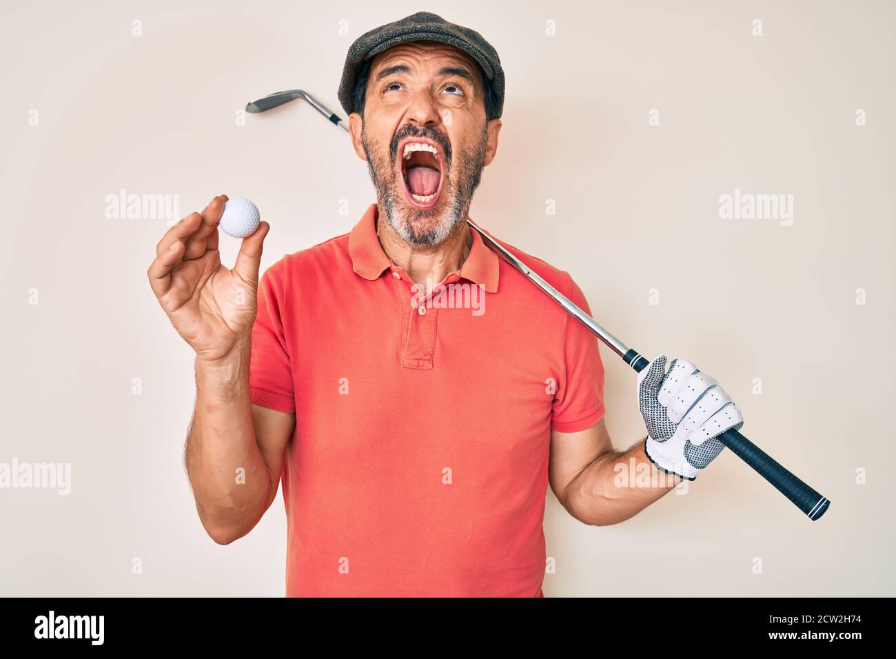 Middle age hispanic man holding golf club and ball angry and mad ...