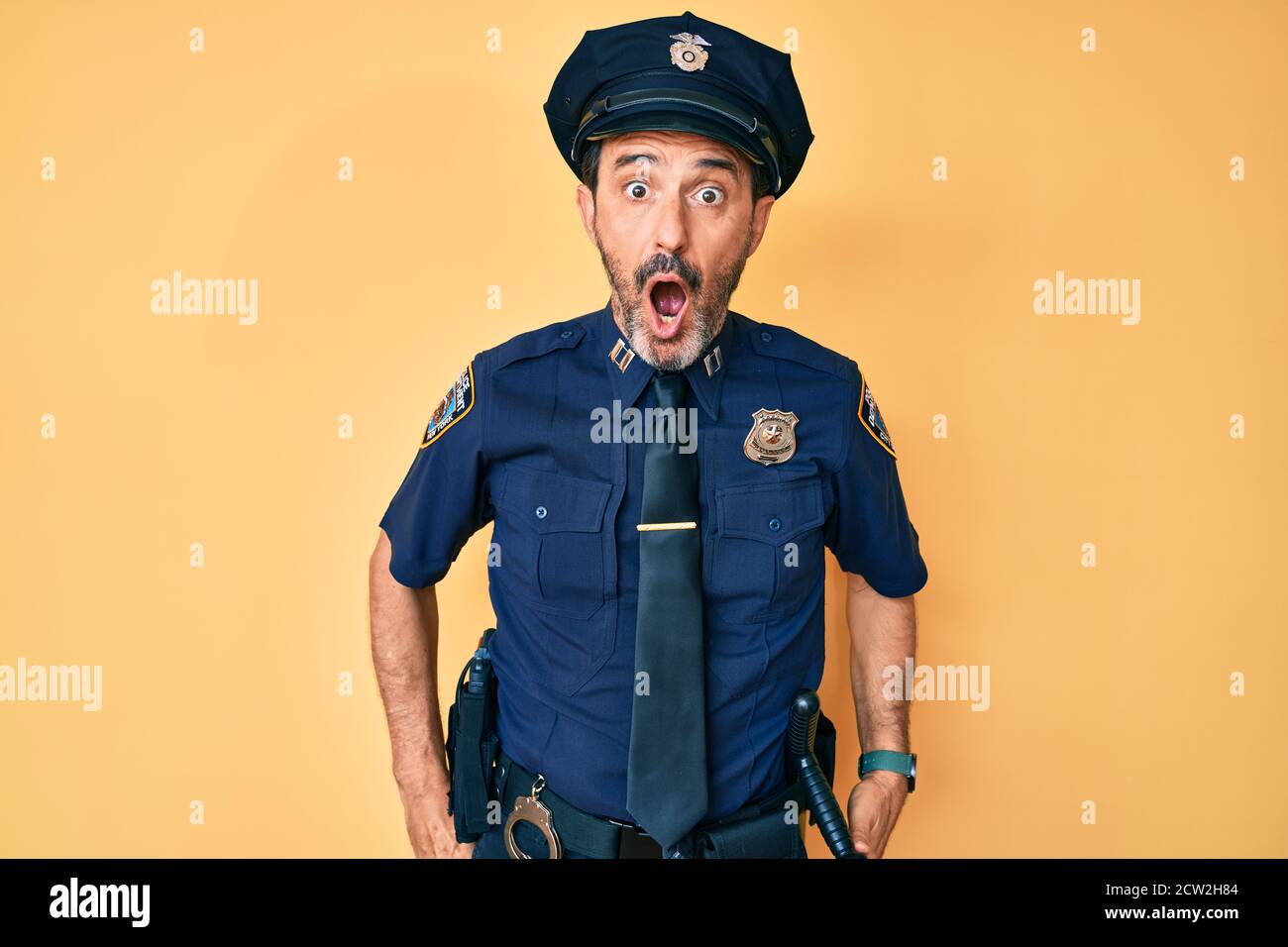 Middle age hispanic man wearing police uniform afraid and shocked with ...
