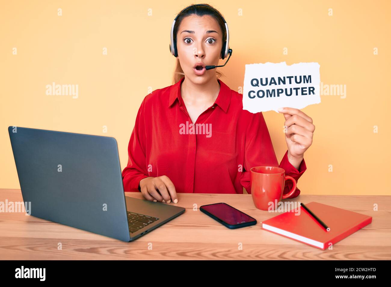 Young brunette woman holding quantum computer banner scared and amazed ...