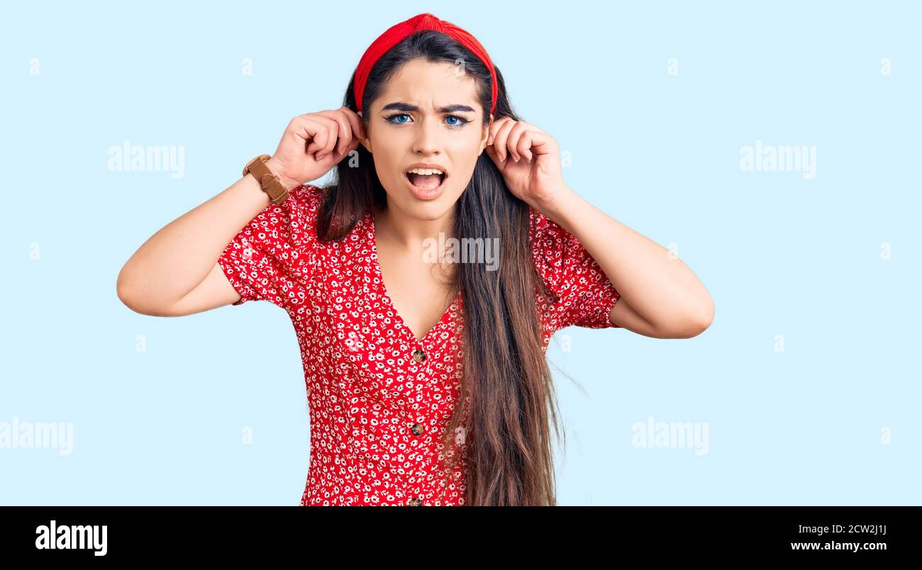 Brunette teenager girl wearing summer dress smiling pulling ears with ...