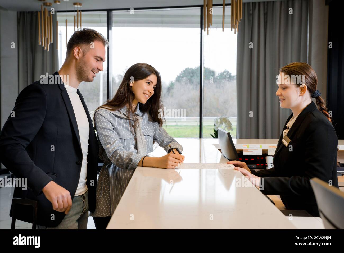Couple and receptionist at counter in hotel. Young couple on a business ...
