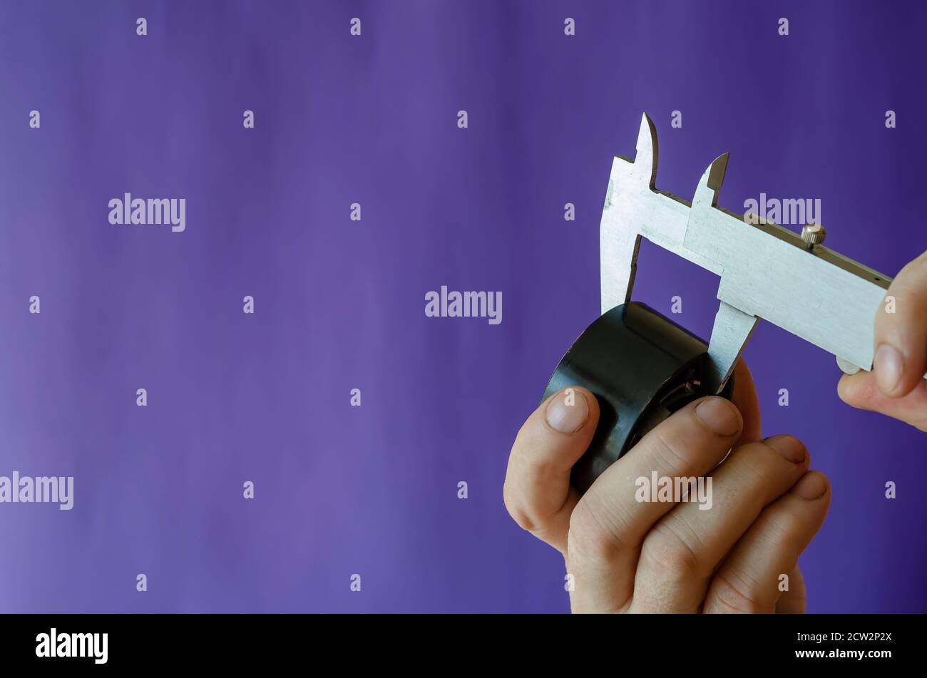Vernier caliper and timing belt tensioner in hand on blue background ...