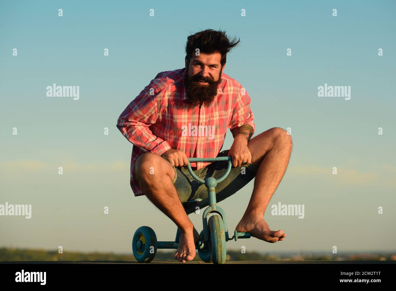 Funny hipster man riding a small bicycle Stock Photo - Alamy