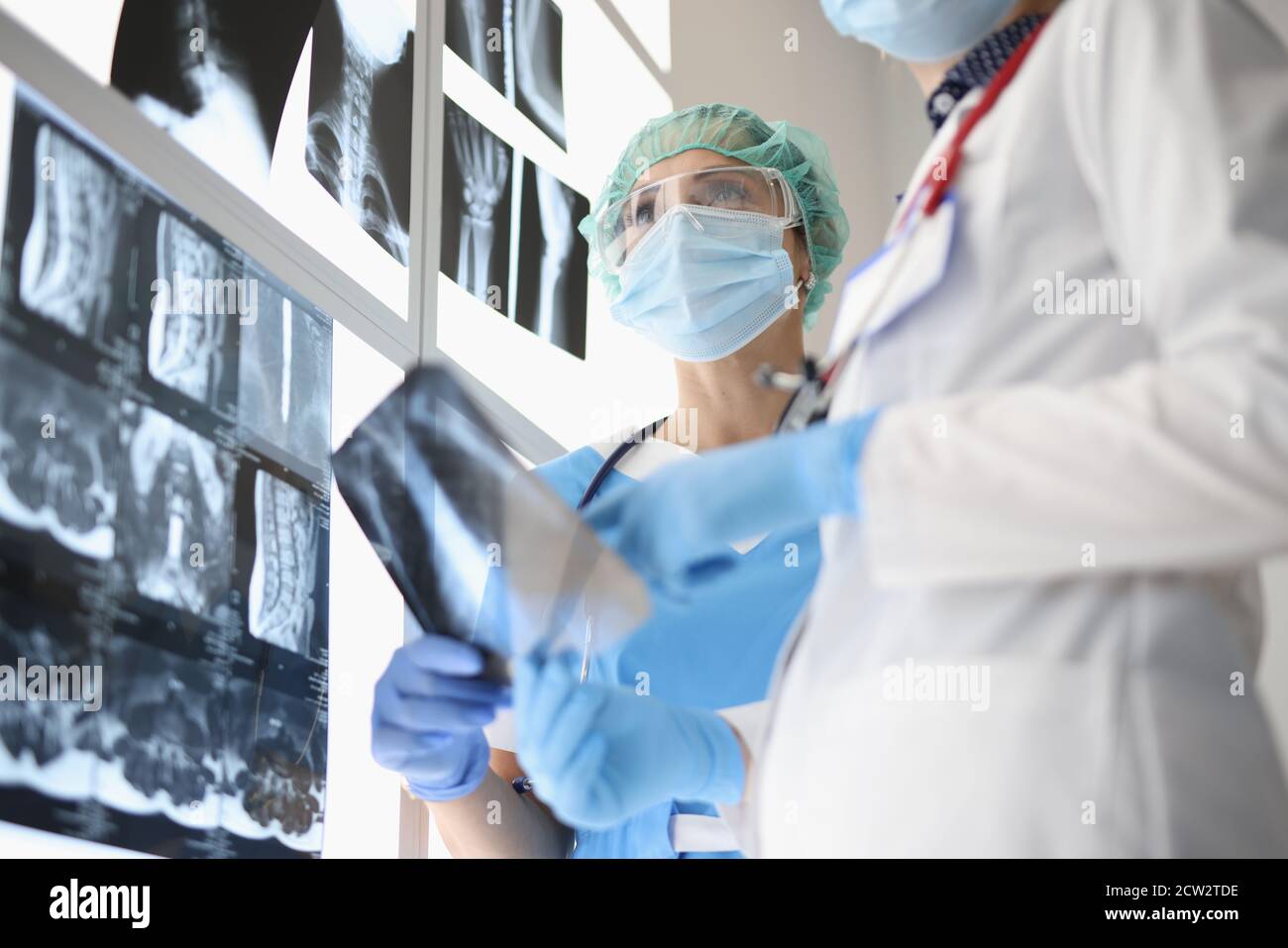 Two medical staff wearing protective masks looking at X-rays Stock ...