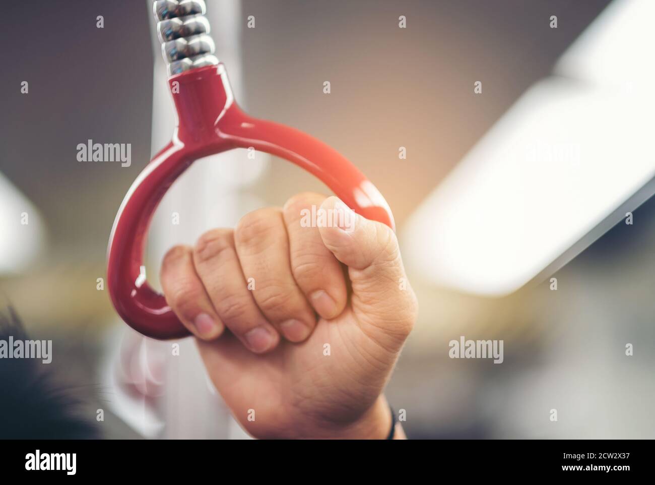 people holding hand onto a handle on a train Stock Photo - Alamy