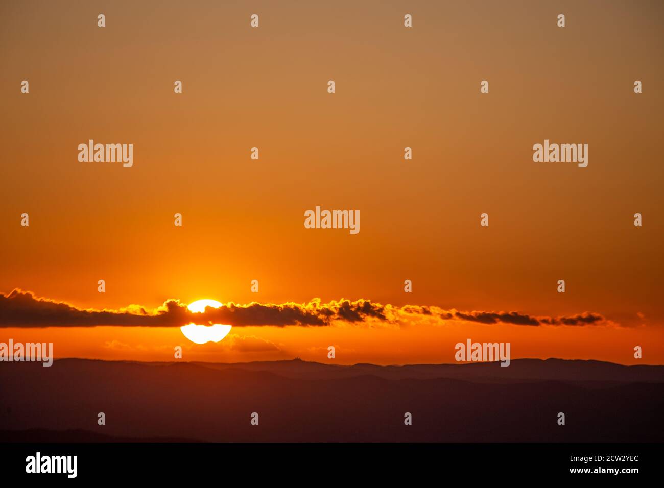 Sunset over mountains and valley, with sun coming down behind some ...