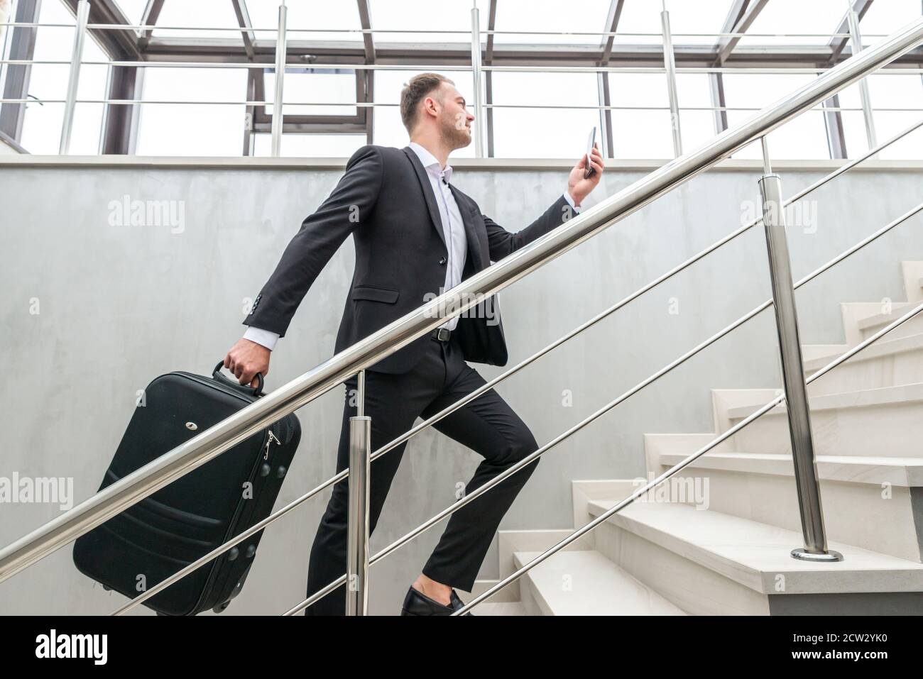 Businessman holding suitcase running on stairs in modern building Stock ...