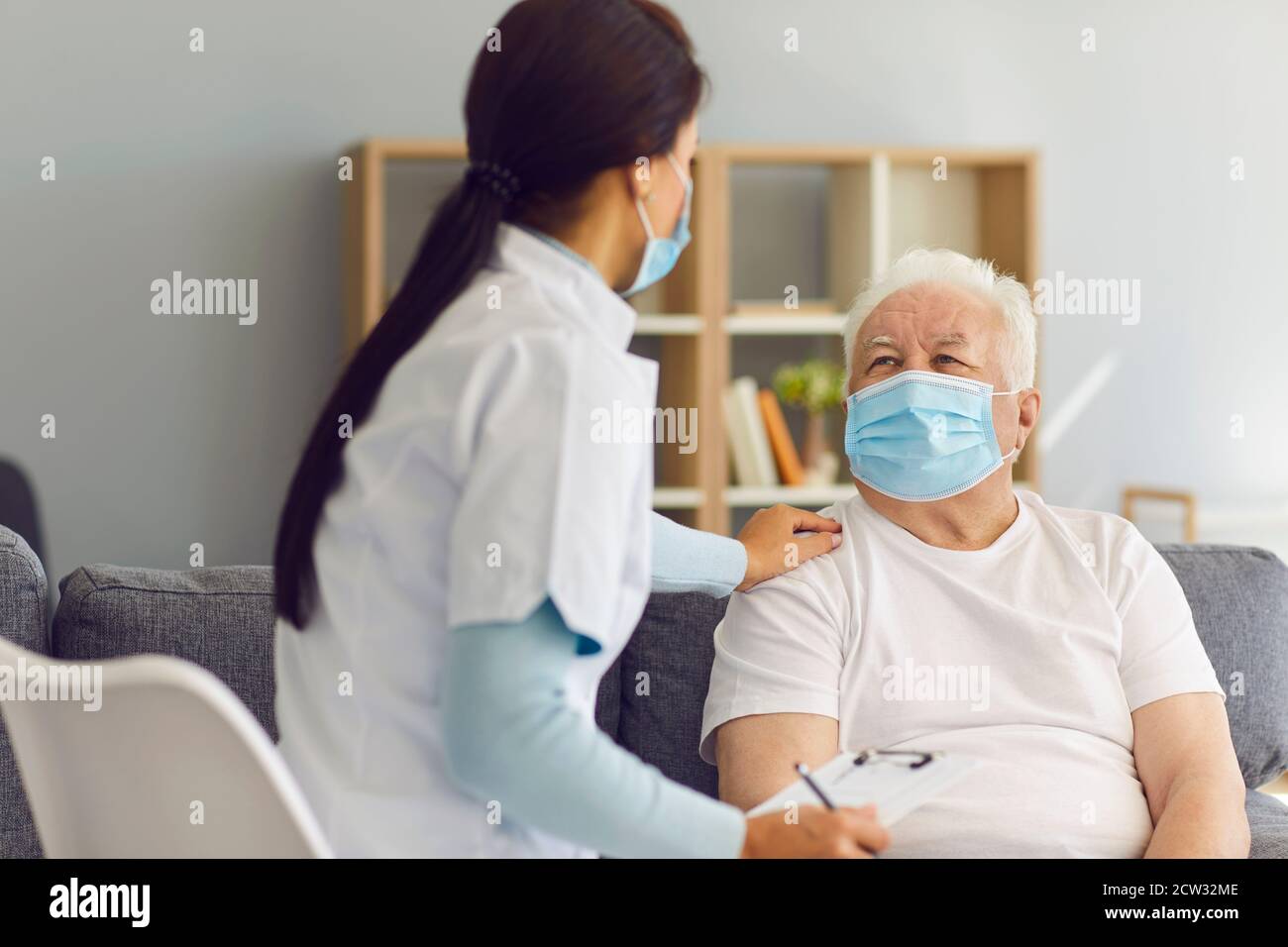 Caring supportive doctor visiting senior male patient at home during ...