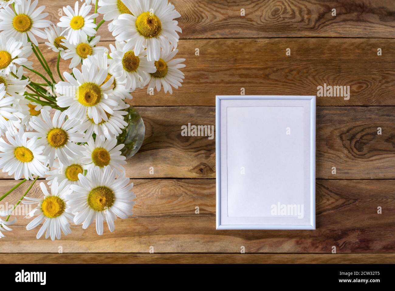 White small frame mockup with daisy wildflowers. Empty frame mock up ...