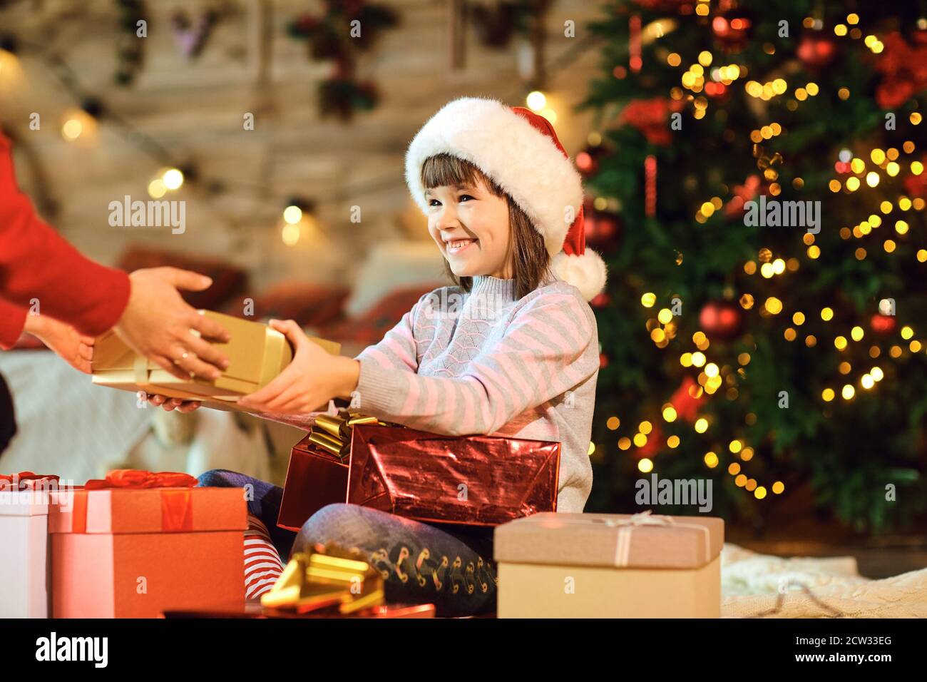 Cheerful girl receiving Christmas gift from parent Stock Photo - Alamy