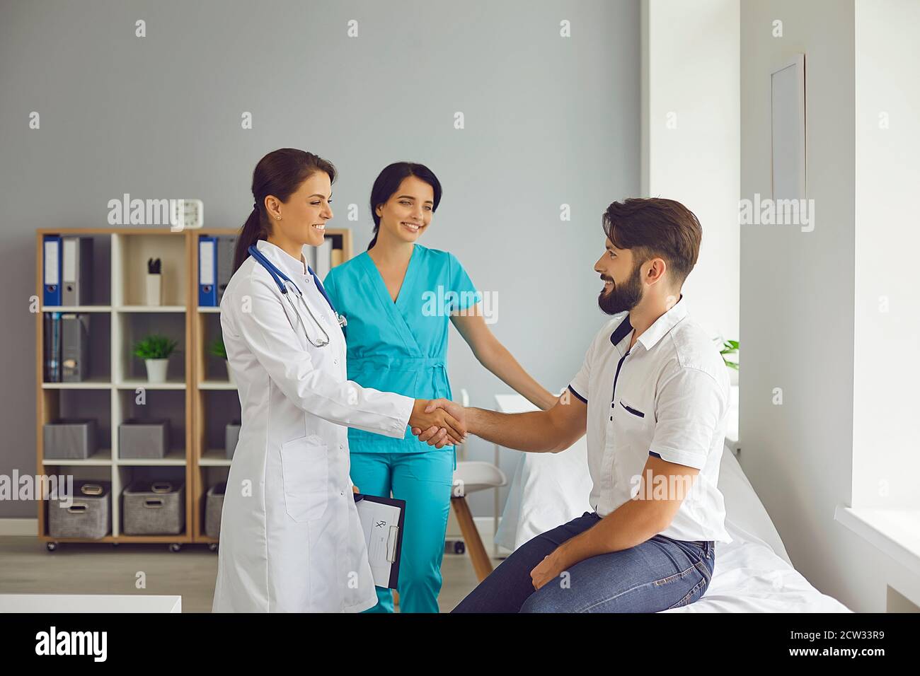 Smiling patient gives a handshake to his doctor at the clinic after the ...