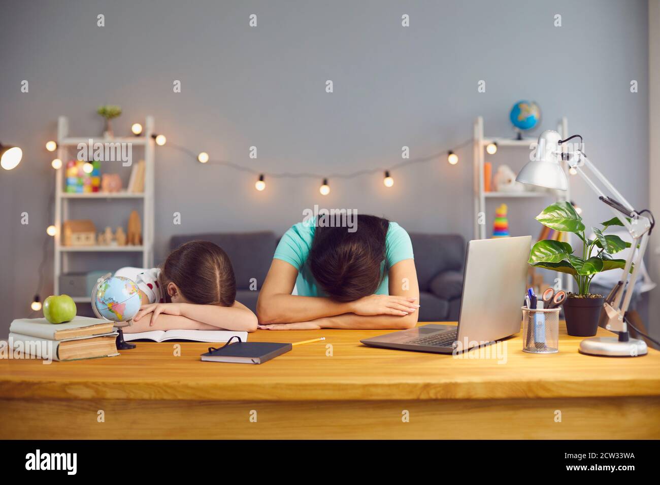 Tired mother and baby sleep lying on the table after a lesson at home ...