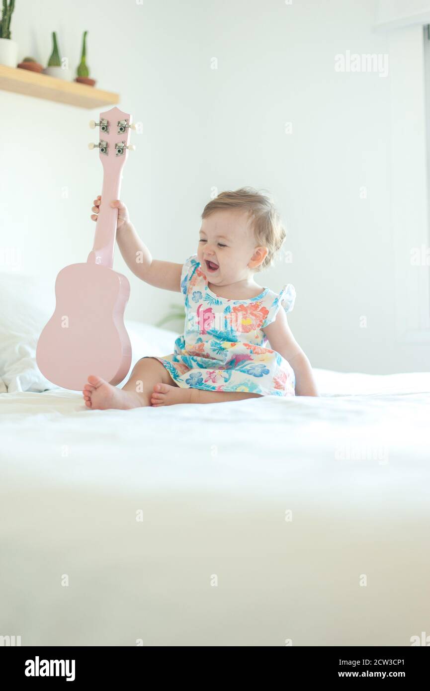 Baby playing ukulele in bed Stock Photo - Alamy