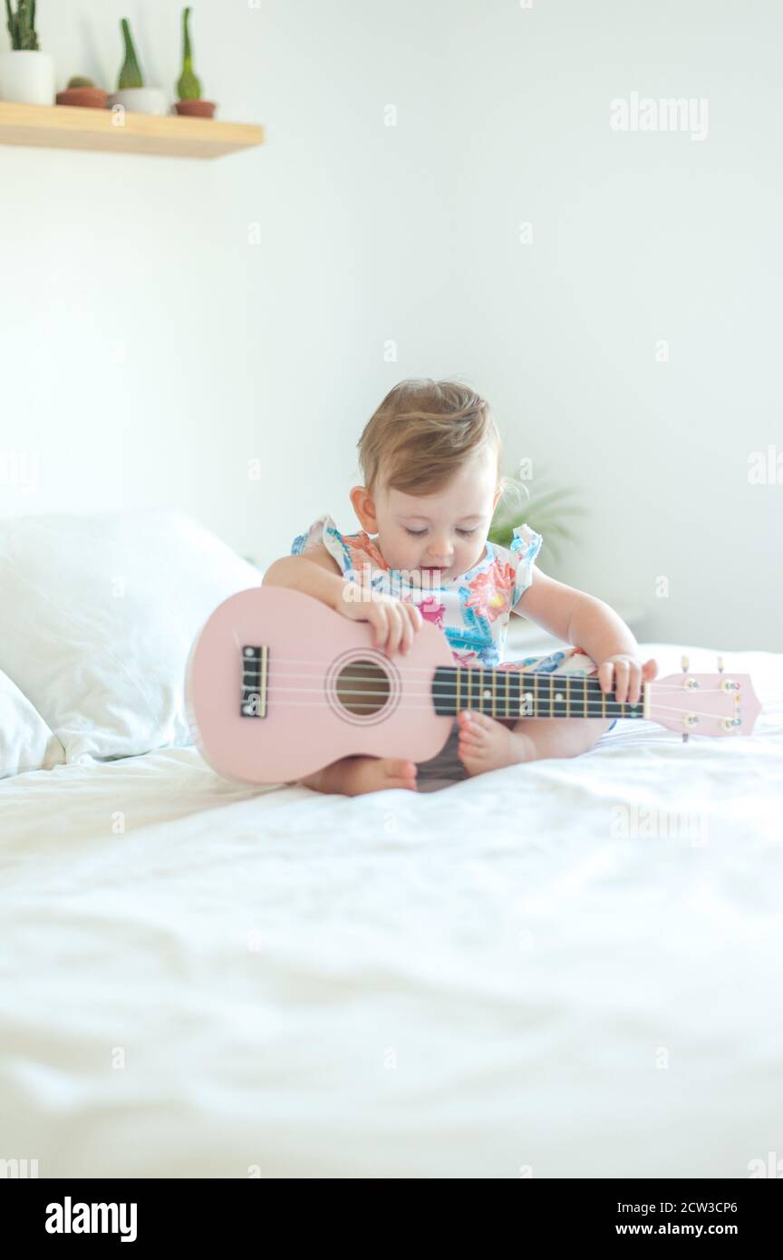 Baby playing ukulele in bed Stock Photo - Alamy
