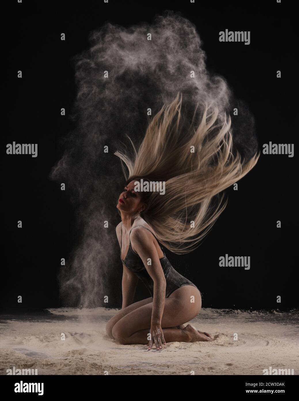 Beautiful sensual slim dancer throwing dust, flour, powder on black background Stock Photo - Alamy