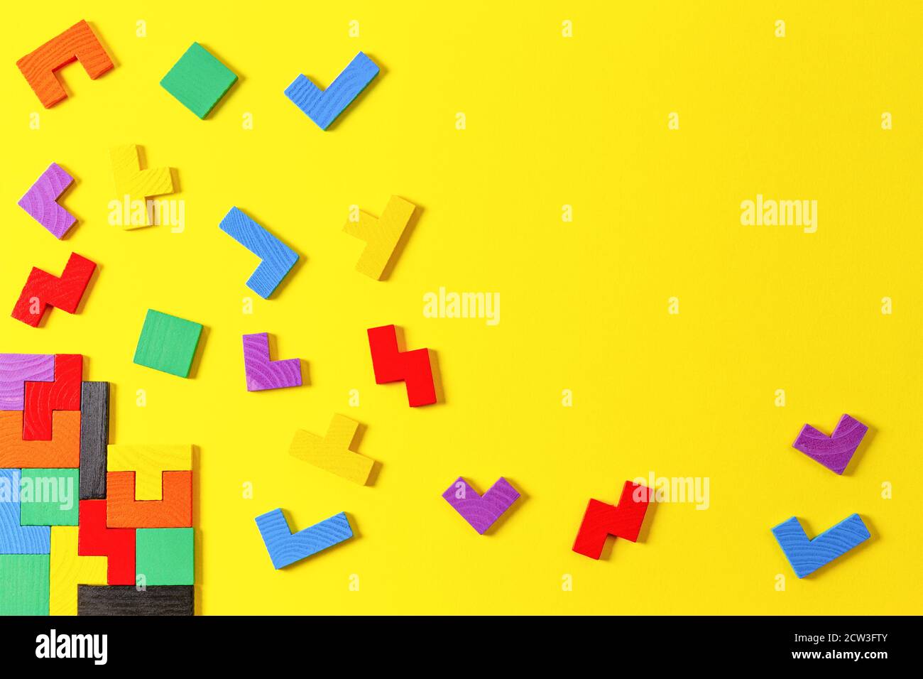 Different colorful shapes wooden puzzle blocks on yellow background ...