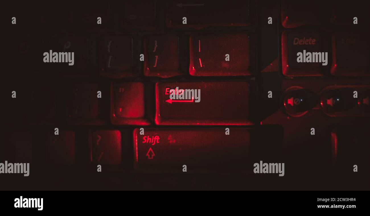 Red light is highlighting on keyboard's enter button in dark Stock ...