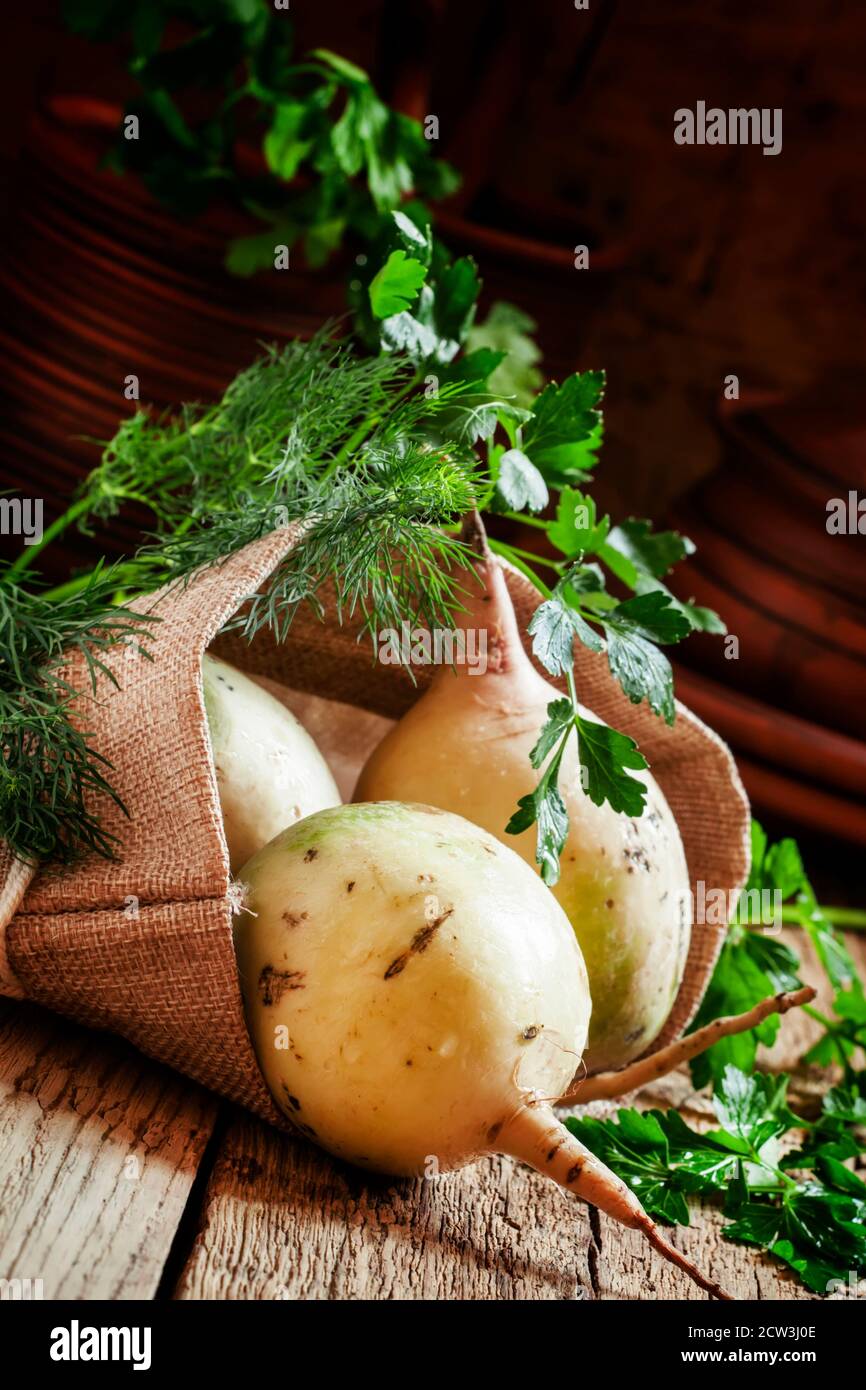 Fresh radish in a canvas bag and herbs on an old wooden background in ...