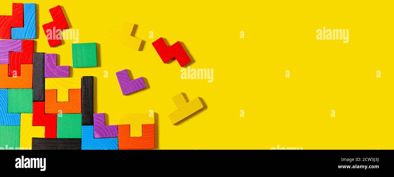 Different colorful shapes wooden puzzle blocks on yellow background ...