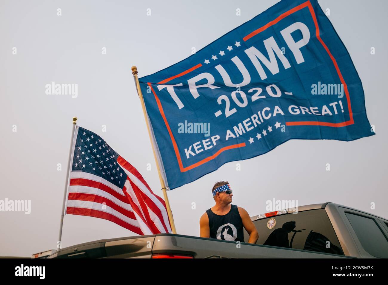 A Trump 2020 supporter stands in the back of his pickup truck flying ...