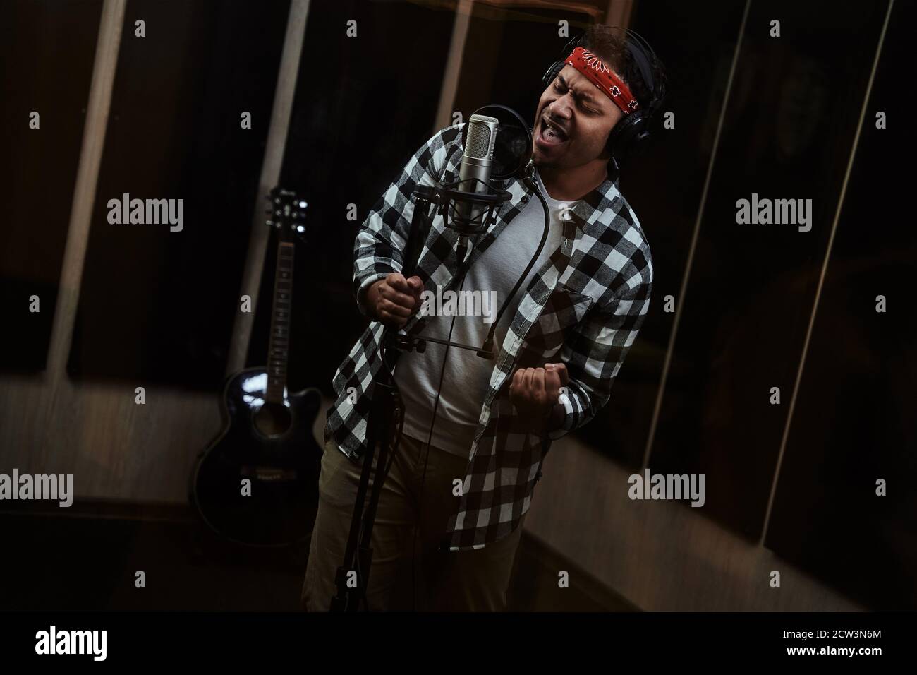 Portrait of young man, male artist looking focused, singing into a ...
