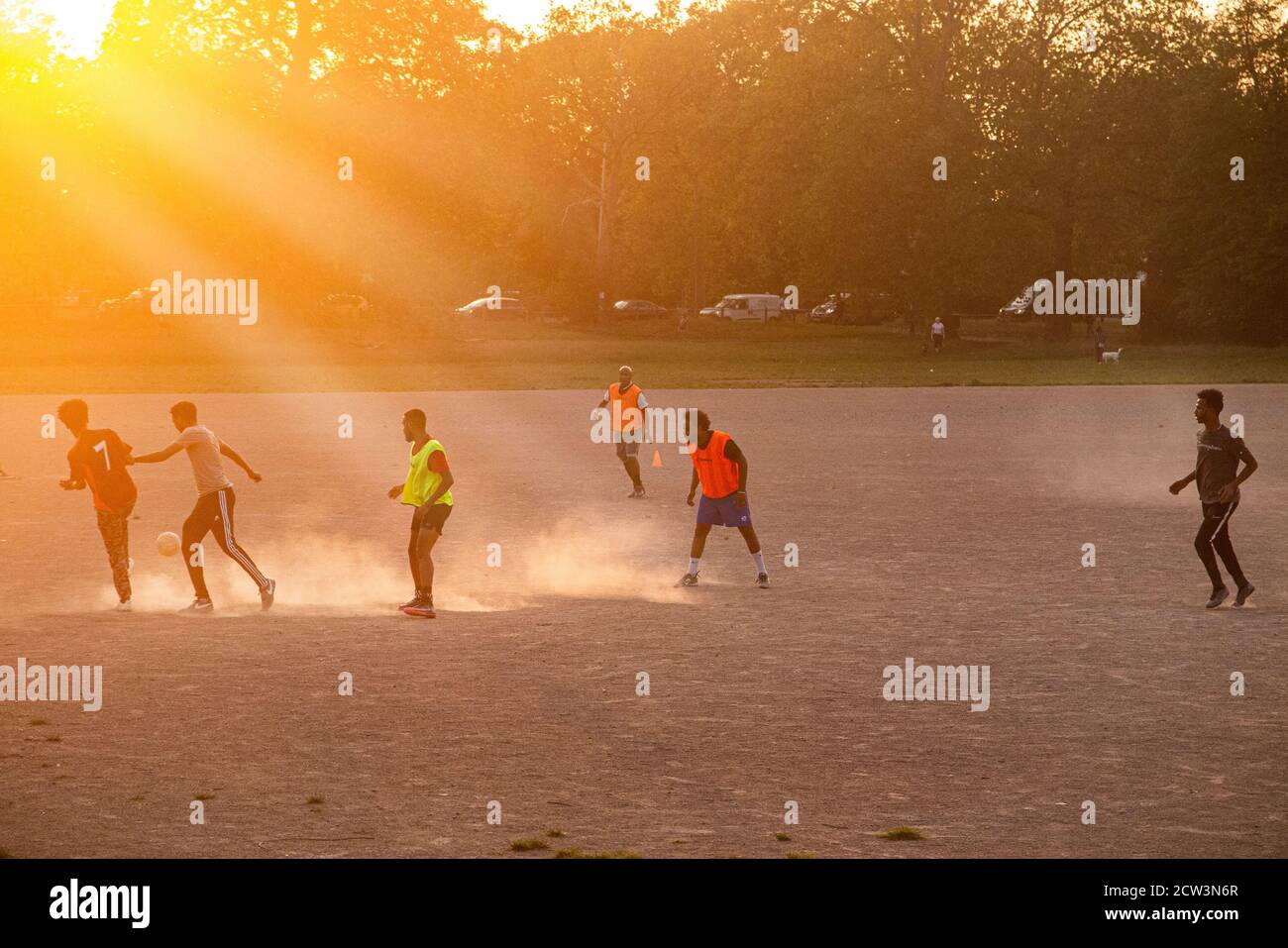 Friends play football on a summers evening on Clapham Common in ...
