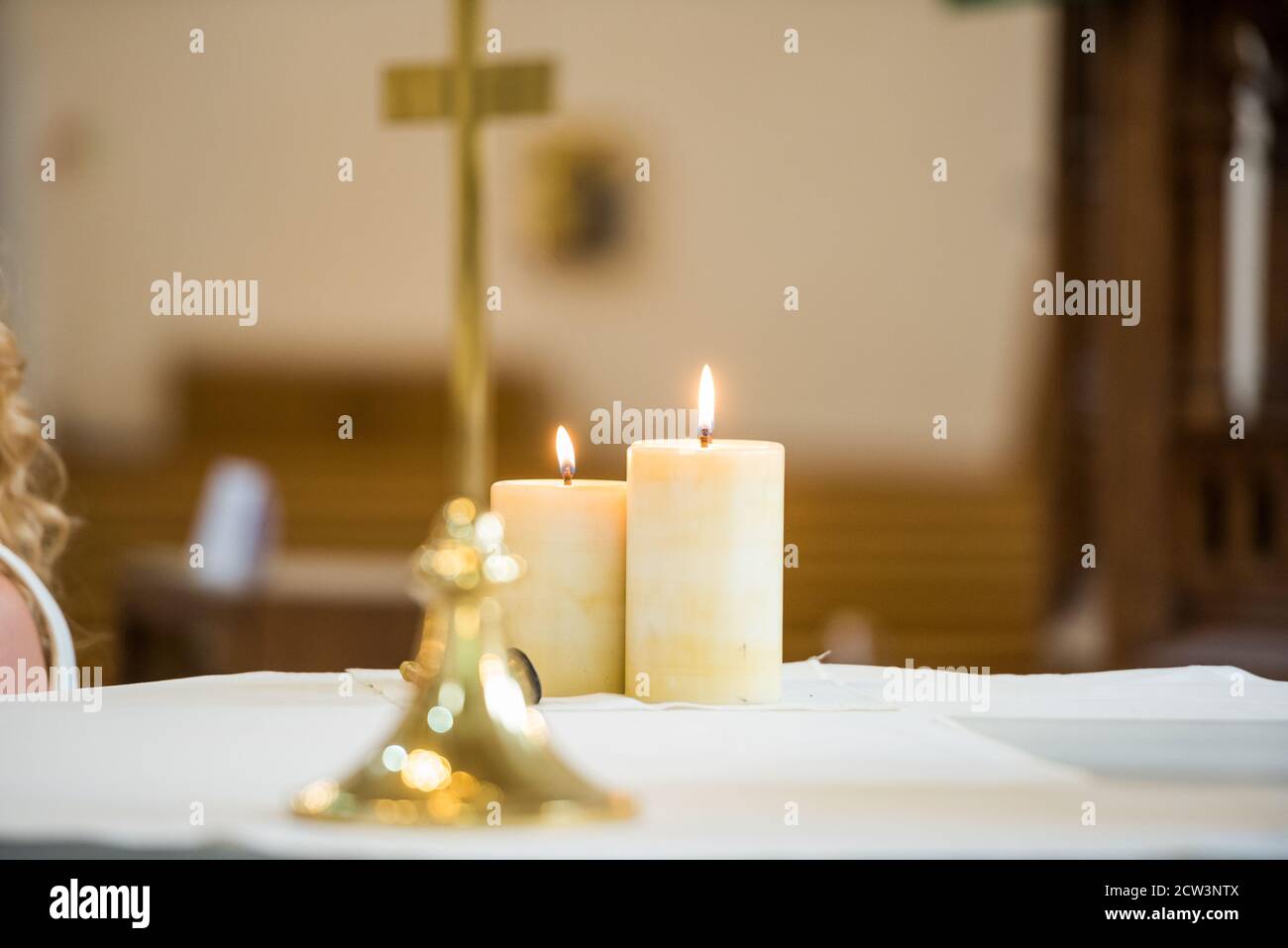 lit white candles on church alter with gold cross in foreground Stock ...