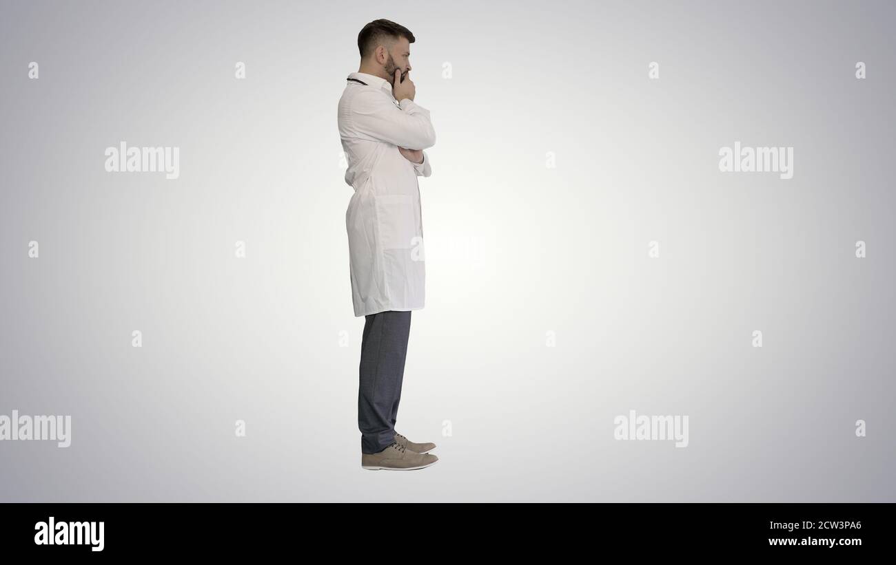 Doctor standing and thinking hard on gradient background Stock Photo ...
