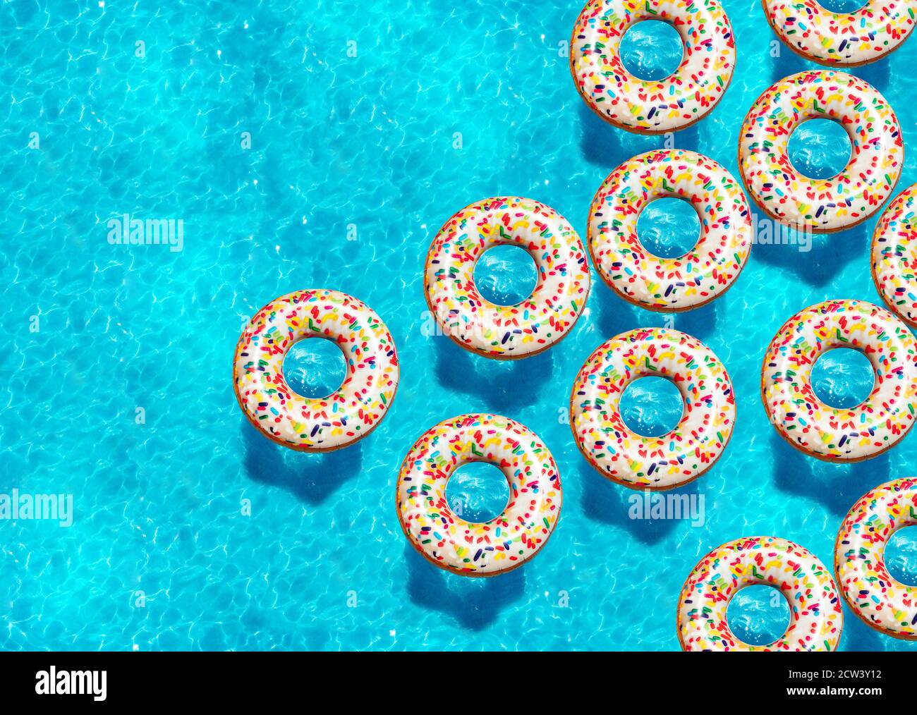 Large group of inflatable candy doughnut buoys swim in the swimming ...
