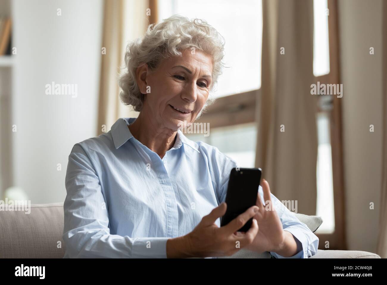 Happy elegant old lady using smartphone with confidence at home Stock ...
