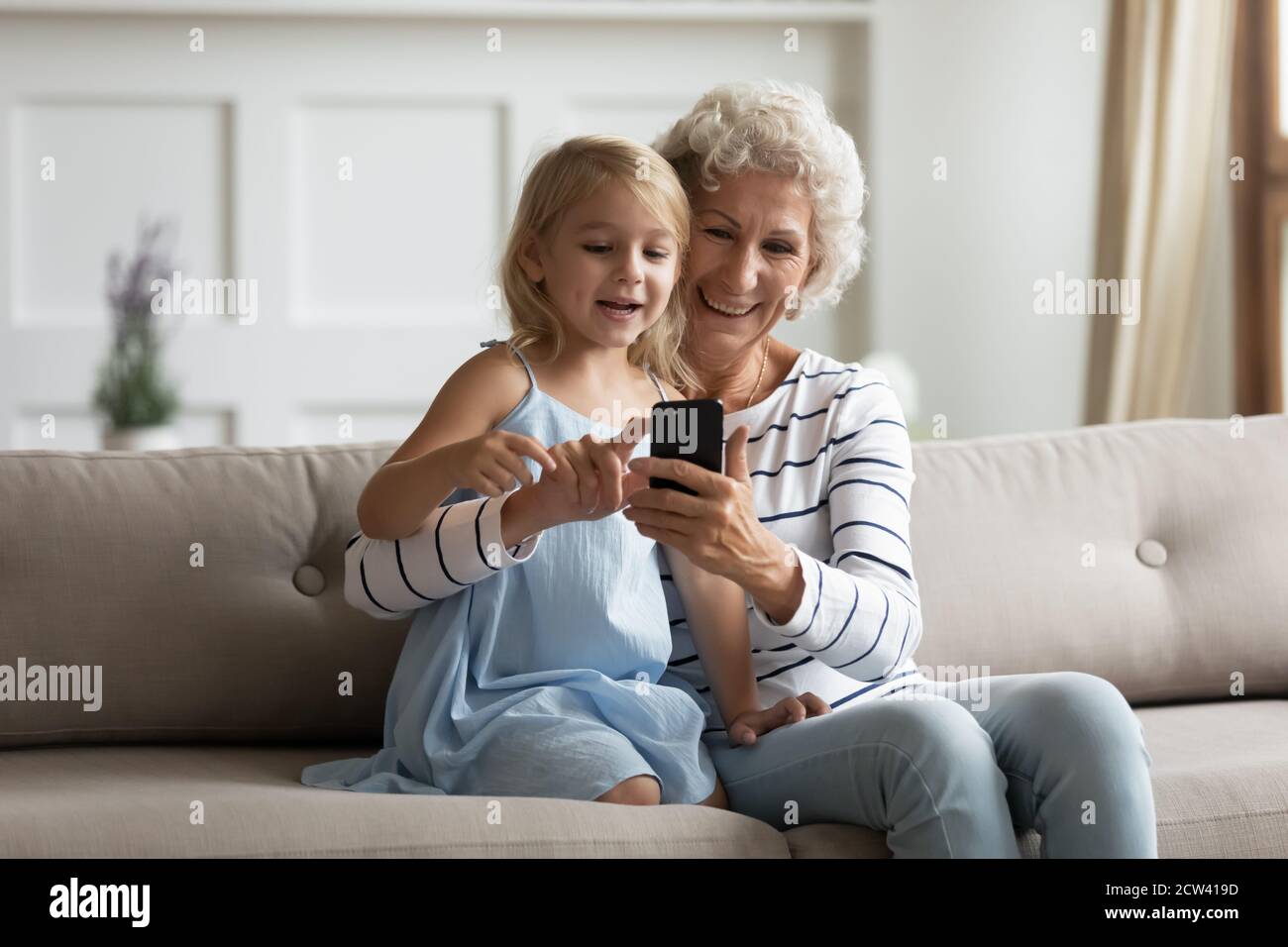 Senior grandma and small granddaughter spending time together using ...
