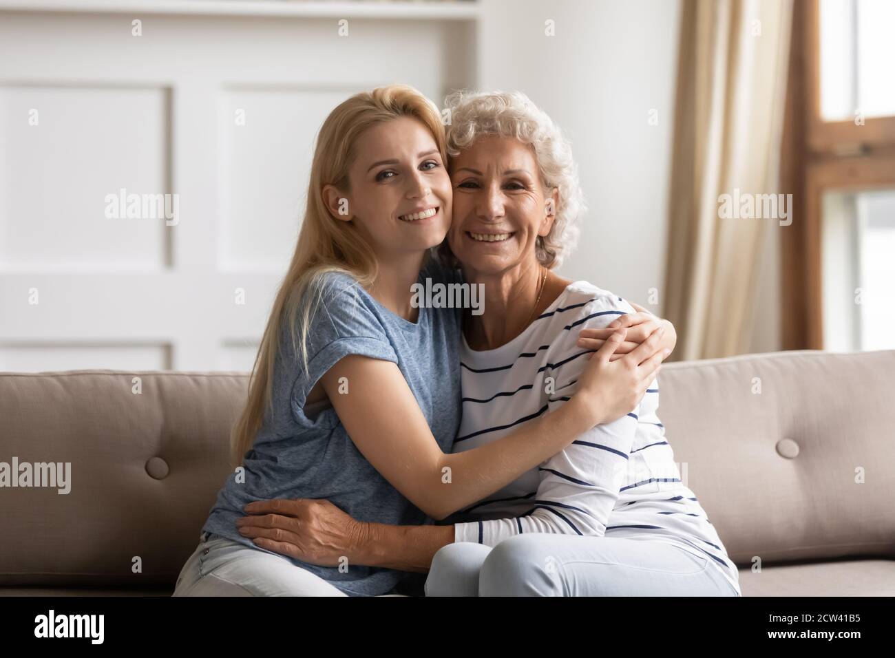 Two happy females of diverse generations posing for portrait indoors ...