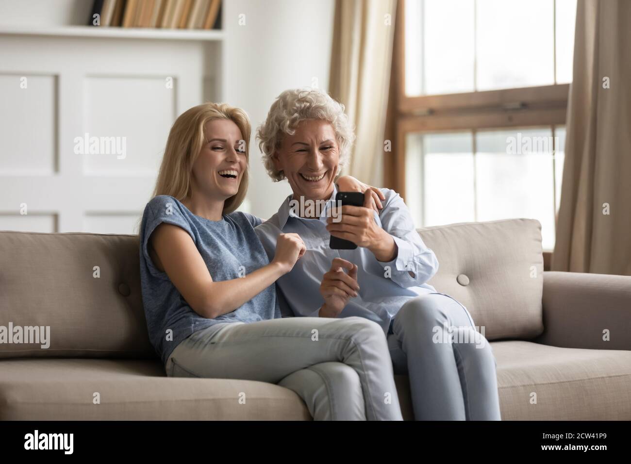 Laughing mature mother embracing millennial child calling relatives by ...
