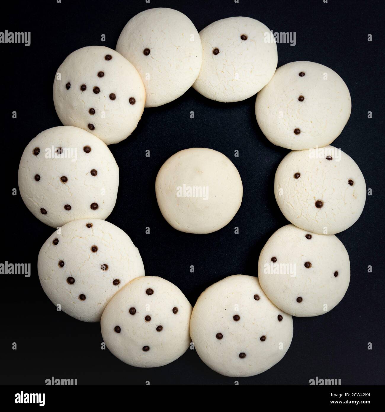 Round shape of white biscuits with dots on black background and one ...