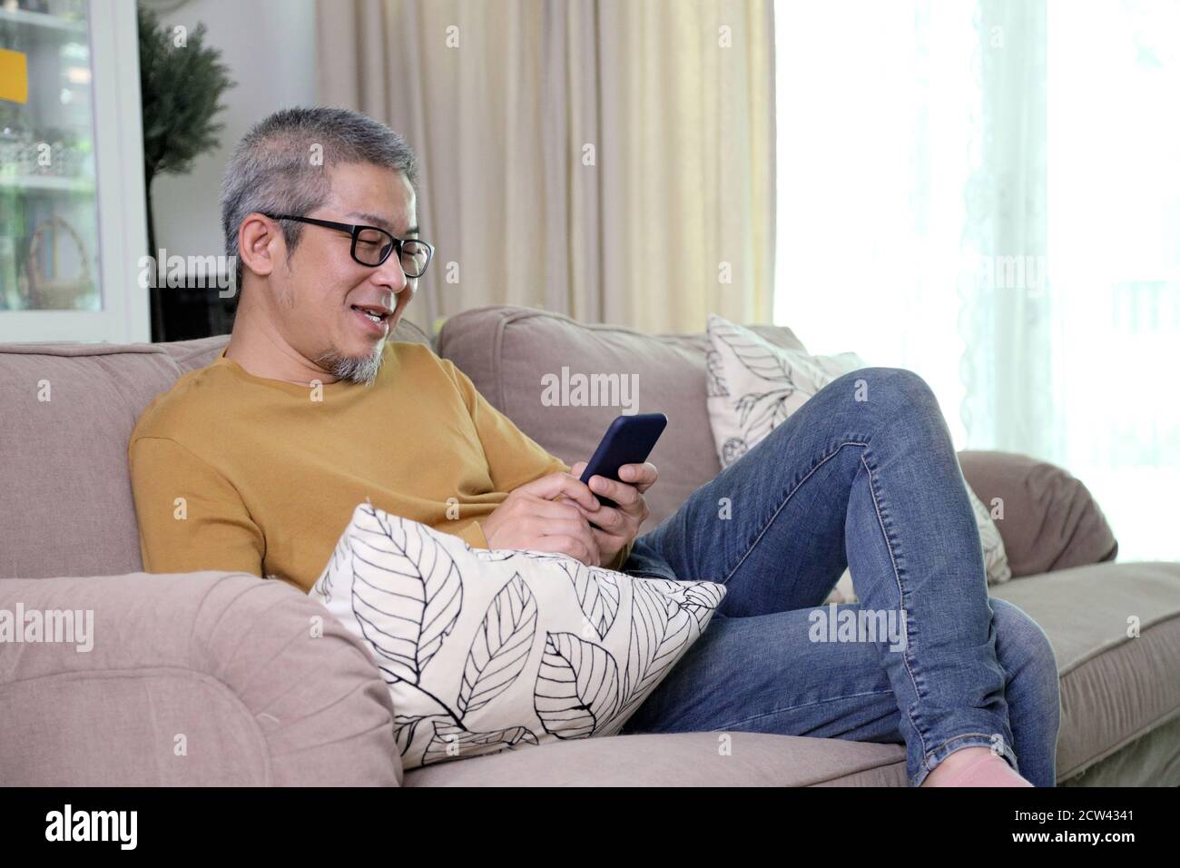 The Asian man relaxing in the living room Stock Photo - Alamy
